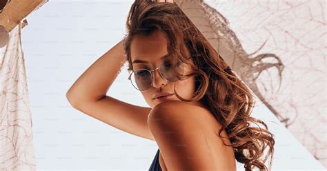 수영복을 입은 매력적인 젊은 여성이 강을 배경으로 해변 오두막에 서 있는 동안 머리카락을 잡고 있다 사진 Unsplash의 관 능 이미지