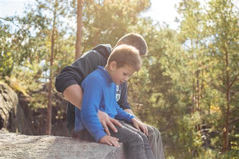 아버지는 아버지와 아들이 함께 보내는 시간을 즐기는 아들을 껴안고 행복한 아이는 이빨을 드러내며 웃고 있습니다 가을 숲 부모 자식 야외에서 행복한 가족 2명에 대한 스톡
