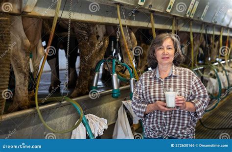 Portrait Of An Elderly Woman Standing Near A Milking Machine Holding A