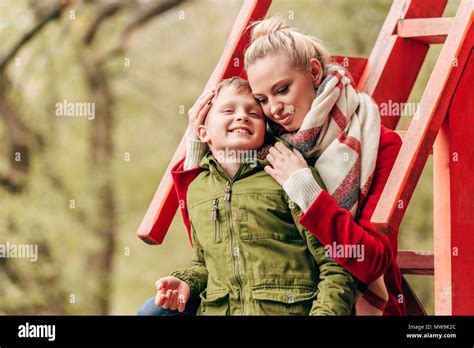 Happy Mother And Son Embracing While Sitting On Wooden Stairs In Autumn