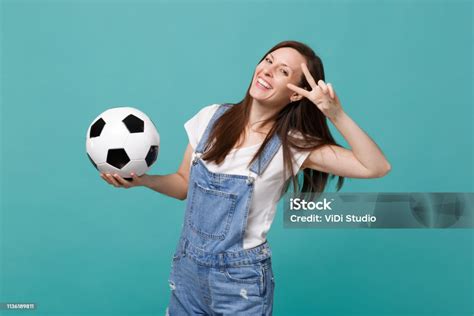 즐거운 여자 축구 팬 응원은 푸른 청록색 배경에 고립 된 승리 기호를 보여주는 축구 공을 좋아하는 팀을 지원 합니다 사람들의 감정 스포츠 가족 레저 개념입니다 복사 공간을