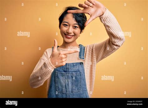 Young Beautiful Asian Girl Wearing Casual Denim Overalls Over Isolated