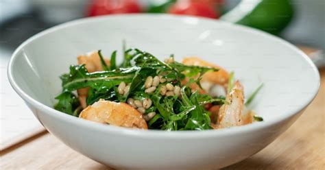 Ruccola 삶은 새우 및 기름이 든 다른 재료로 구성된 식욕을 돋우는 샐러드가 들어있는 흰색 세라믹 그릇이있는 나무 보드 사진 Unsplash의 음식 이미지