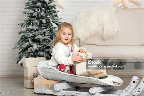 크리스마스는 이미 여기에 있다 크리스마스 선물 상자와 소녀 썰매 작은 귀여운 소녀는 휴일 선물을 받았다 썰매를 타는 동안 아이는 선물 상자를 들고 있습니다 크리스마스를