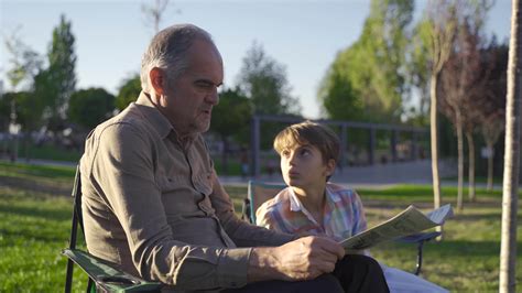 Elderly Man Sitting Outdoors With His Grandson Reading Newspaper Old Man Reading Newspaper