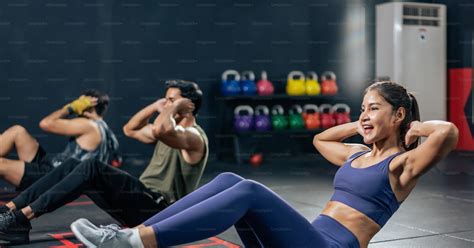 활동적인 스포츠맨과 여자는 경기장에서 복근 운동을 위해 바닥에 윗몸 일으키기를 합니다 체육관에서 건강 관리 라이프스타일을 위한 근육을 만들기 위해 유산소 운동을 하는