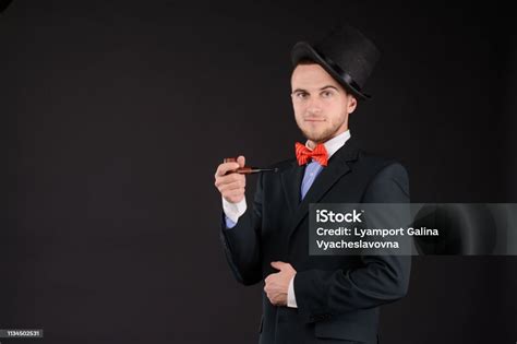 어두운 배경에 실린더 모자와 보우 타이에서 성인 젊은 우아한 남자의 초상화입니다 그의 손에 흡연 파이프를 들고 고전 양식에 대한