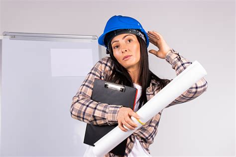 사무실 배경에서 전화로 이야기하는 문서와 프로젝트와 하드 모자를 쓴 젊은 여성 건물 외관에 대한 스톡 사진 및 기타 이미지