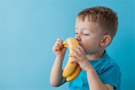 Niño Sosteniendo Y Comiendo Un Plátano Foto Premium
