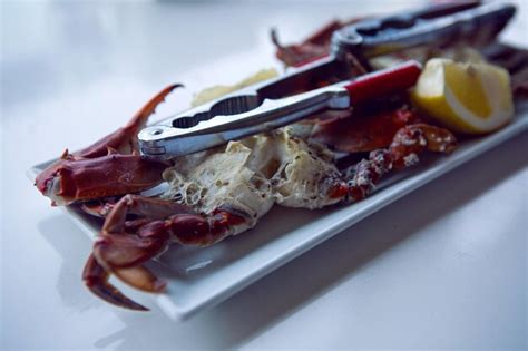 Premium Photo Cut Boiled Blue Crab Lies On A White Plate With Tongs