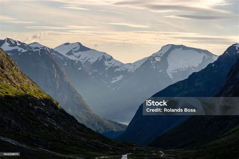 회색 돌 표면이 녹색 이끼로 덮인 큰 산 사이에 큰 깊은 계곡이있는 산 풍경이지만 산 정상에는 눈이 있고 산 위에 아름다운 하늘이 있습니다 노르웨이에 대한 스톡 사진 및