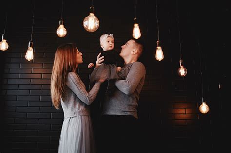 젊은 가족 아빠 엄마와 아기 소녀의 초상화는 집에서 함께 시간을 즐길 수 있습니다 전경에 복고풍 전구 크리스마스 시간 20 24세에 대한 스톡 사진 및 기타 이미지 Istock