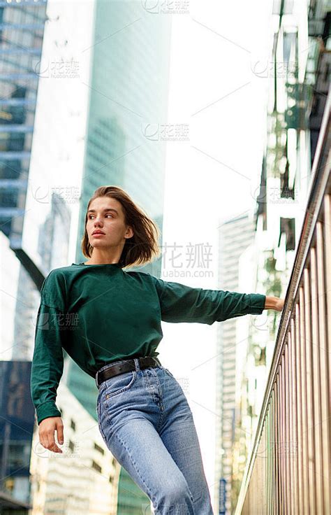 酷女孩，一头金色短发，穿着蓝色和牛仔裤，在粗糙的街道墙上摆姿势，极简的城市服装风格，夕阳背景