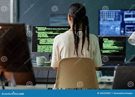 Female Programmer Coding On Multiple Computers At Professional Workstation In Office Stock Image