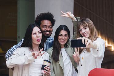 Lächelnde Geschäftsfrau nimmt Selfie durch Handy mit männlichen und