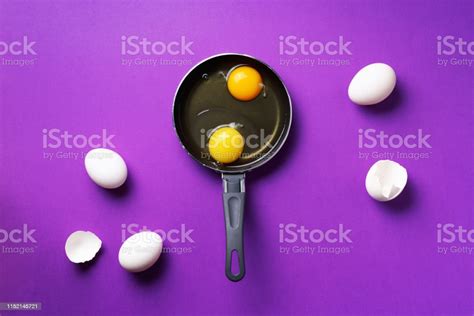 두 개의 계란 포탄 보라색 배경에 냄비와 음식 개념입니다 평면도 최소한의 스타일로 창조적 인 패턴 평평한 누워 개념에 대한 스톡