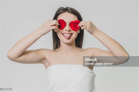 흰색 바탕에 서 있는 젊은 예쁜 여자 그 동안 그녀의 눈을 덮고 빨간 꽃잎으로 그녀의 팔을 올렸다 혀를 보여줍니다 가꿔주기에