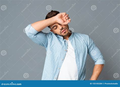 Exhausted Hispanic Man Wiping Sweat Off Forehead On Gray Background