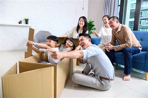 거실에서 종이 판지 배를 가지고 놀고 소파에 앉아있는 조부모가 지켜보는 다세대 가족 25 29세에 대한 스톡 사진 및 기타 이미지 25 29세 30 34세 4 5세