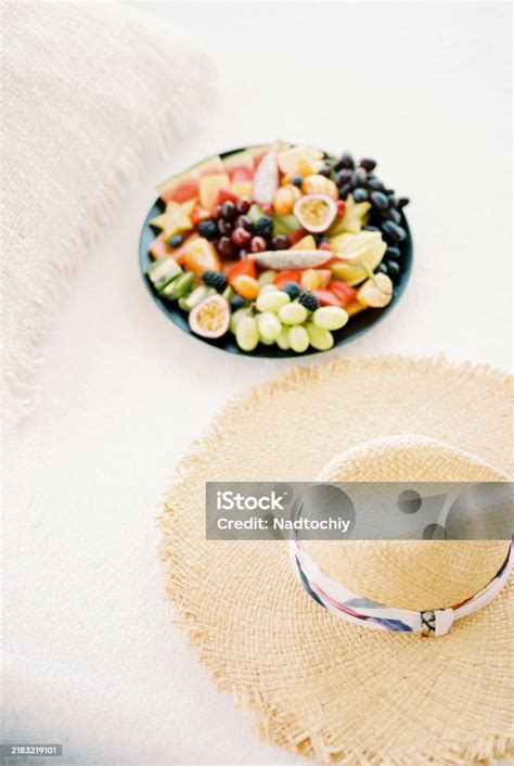 잘게 썬 과일 접시가 밀짚모자 옆 침대 위의 하얀 시트 위에 놓여 있습니다 과일에 대한 스톡 사진 및 기타 이미지 과일 관광 관광 리조트 Istock