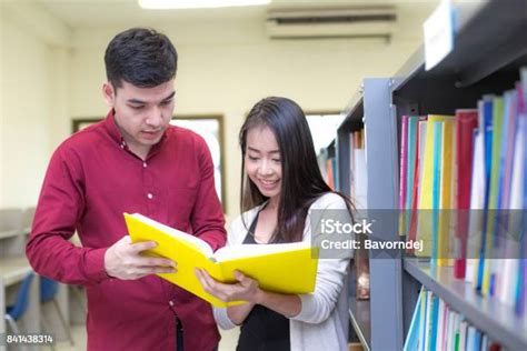 포그라운드에서 학생 독서에 대 한 책을 들고 있다 젊은 아시아 학생 함께 현대 도서관에서 책을 읽고 있다 교육 개념을 가진 사람들입니다 2명에 대한 스톡 사진 및 기타