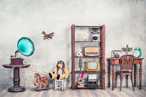 골동품은 여전히 오래된 축음기 테디 베어 흔들 말과 오래된 미디어 뉴스 제작자 및 작가 장치 앞 콘크리트 벽 배경의 컬렉션과