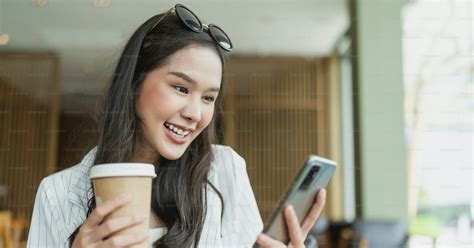매력적인 스마트 캐주얼 아시아 여성 손 타이핑 채팅 스마트폰 통신 사용 긍정적인 태도 카페 캐주얼에서 미소 카페에서 스마트폰으로 일하는 똑똑한 사업주 기업가 사진