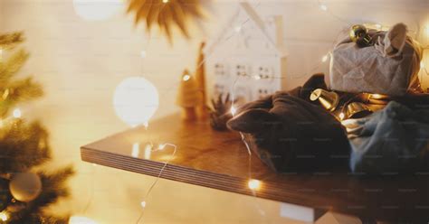 작은 집 나무 종이 별 크리스마스 황금빛 조명 보케를 배경으로 나무 선반에 있는 세련된 제로 웨이스트 크리스마스 선물 축제 장식 스칸디나비아 객실 대기 이브 사진