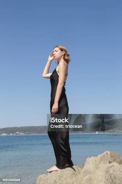 뒤에 아름 다운 고요 한 바다 세련 되 고 우아한 여름 패션 해변에서 검은 실크 드레스를 입은 여성 모델의 야외 초상화 35