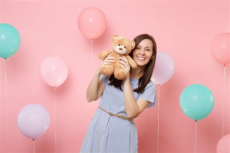 다채로운 공기 풍선 파스텔 핑크 바탕에 테 디 베어 봉 제 장난감을 들고 파란 드레스를 입고 웃는 예쁜 젊은 여자의 초상화 생일 휴가 파티 사람들이 진심으 감정 개념 14에