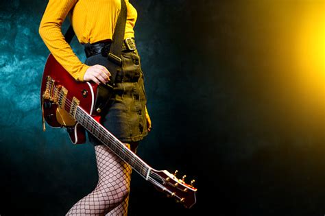 네온 불빛에 젊은 소식통 여자 다리와 레드 기타의 클로즈업 사진 록 뮤지션은 일렉트릭 기타를 연주하 고 있습니다 90 년대 스타일의 개념입니다 기타 연주자에 대한 스톡 사진