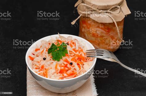 흰색 그릇에 당근과 검은 배경에 유리 항아리에 수제 소금에 절인 양배추 비건 및 채식 발효 식품 갈기갈기 찢어진에 대한 스톡