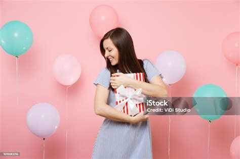블루 드레스를 포옹 선물 다채로운 공기 풍선 파스텔 핑크 배경에 빨간색 상자가 부드러운 매력적인 여자의 초상화 생일 휴가 파티 사람들이 진심으 감정 14에 대한 스톡 사진