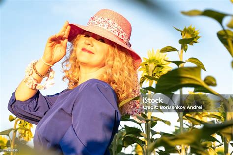 해바라기밭에 분홍색 모자를 쓴 소녀 물결 모양의 갈색 머리와 파란색 드레스를 입은 여성 해가 진 후 태양 가을에 대한 스톡 사진 및 기타 이미지 Istock