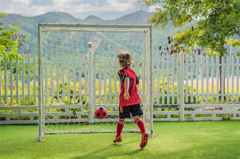 빨간 축구 유니폼을 입은 귀여운 소년이 야외에서 축구 축구를 하고 있다 아이들이나 아빠와 함께 스포츠를 하는 활동적인 아이