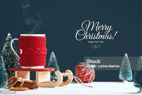 메리 크리스마스 비문 크리스마스 카드입니다 장난감 나무 빨간 그릇 계 피 스틱 및 슬라이스 어두운 배경에 산타 클로스 썰매에 빨간 니트 옷에 뜨거운 코코아와 화이트 컵