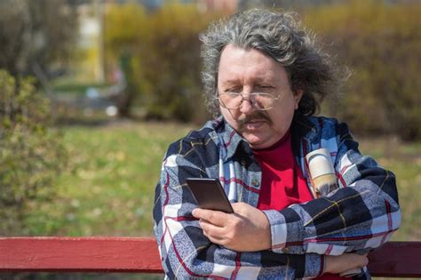Premium Photo Adult Man Sitting In The Park And Reading News On The Phone
