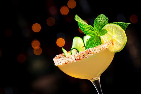 데킬라 라임 주스 시럽 민트 얼음을 곁들인 오이 마가리타 알코올 칵테일 음료는 소금에 절인 치오이 고추 테두리 어두운 배경 바 도구 및 병으로 장식되어 있습니다 마르가리타에