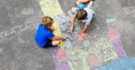 두 어린 소년이 아스팔트에 화려한 분필로 기사 성을 그리고 있다 행복한 형제 자매와 친구들은 분필 그림과 그림을 그리는 데 재미를 느낍니다 여름철 어린이를 위한 창의적