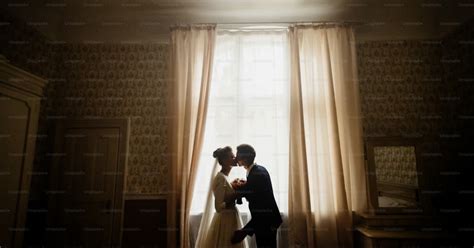 풍부한 방에서 창가에 서 있는 행복한 럭셔리 신부와 신랑 부드러운 순간 사진 Unsplash의 아내 이미지