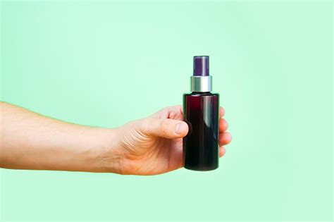 녹색 배경에 브랜드가없는 갈색 플라스틱 스프레이 병과 남성 손의 모형 의약품 또는 화장품 의 브랜딩을위한 화장품 병 용기 천연 유기농 스파 바디 미스트 갈색에 대한 스톡