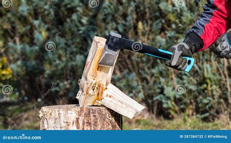 Closeup Of Sharp Axe In Human Hand When Splitting Wood Log On Chopping Block In Garden Stock