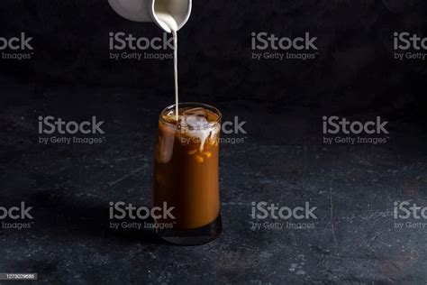 키가 큰 유리에 얼음 커피 Frappe 낮은 키의 어두운 배경에 시원한 여름 음료 커피에 우유 한 줄기가 쏟아져 들어옵니다 닫기 텍스트에 대한 공간을 복사 냉동된에 대한