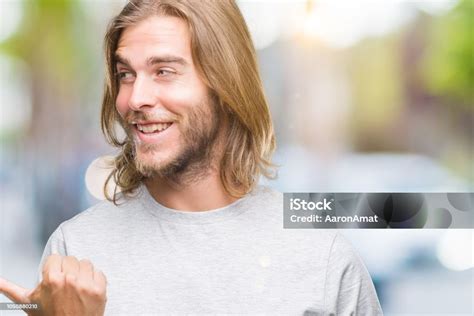 생기고 엄지 측면 가리키는 행복 한 얼굴로 웃 고 고립 된 배경 위에 긴 머리를 가진 젊은 잘생긴 남자 가리키기에 대한 스톡 사진 및 기타 이미지 Istock