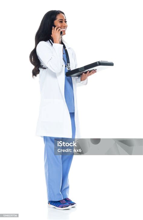 라틴 아메리카와 히스패닉 인종 젊은 여성 의사는 실험실 코트를 입고 서류를 들고 스마트 폰을 사용하여 흰색 배경 앞에 서 20 24세에 대한 스톡 사진 및 기타 이미지