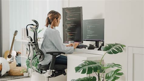 Young Asian Woman Software Developers Using Computer To Write Code Sitting At Desk With Multiple