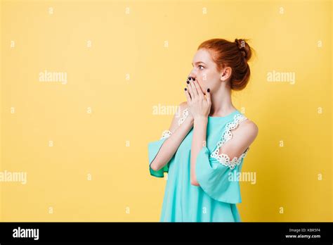 Surprised Ginger Woman In Dress Looking Away And Covering Her Mouth