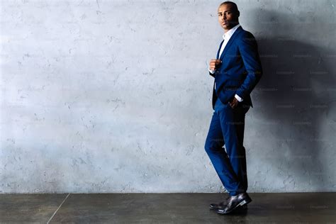 검은 양복을 입은 웃는 사업가가 카메라를 보고 회색 배경에 고립되어 서 있다 사진 Unsplash의 양복 이미지