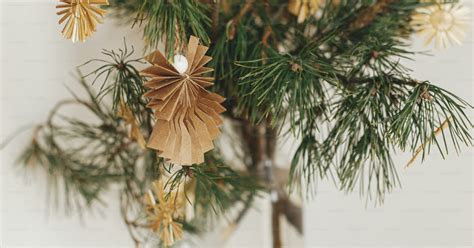 세련된 크리스마스 별 밀짚 장식품과 종이 천사는 스웨덴 별을 배경으로 꽃병에 있는 테이블에 있는 소나무 가지에 있습니다 축제 장식 스칸디나비아 객실 에코 플라스틱 무료