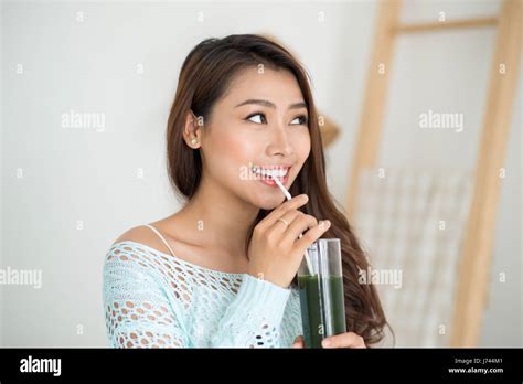 Pretty Young Asian Woman Drinking Green Fresh Vegetable Juice Or